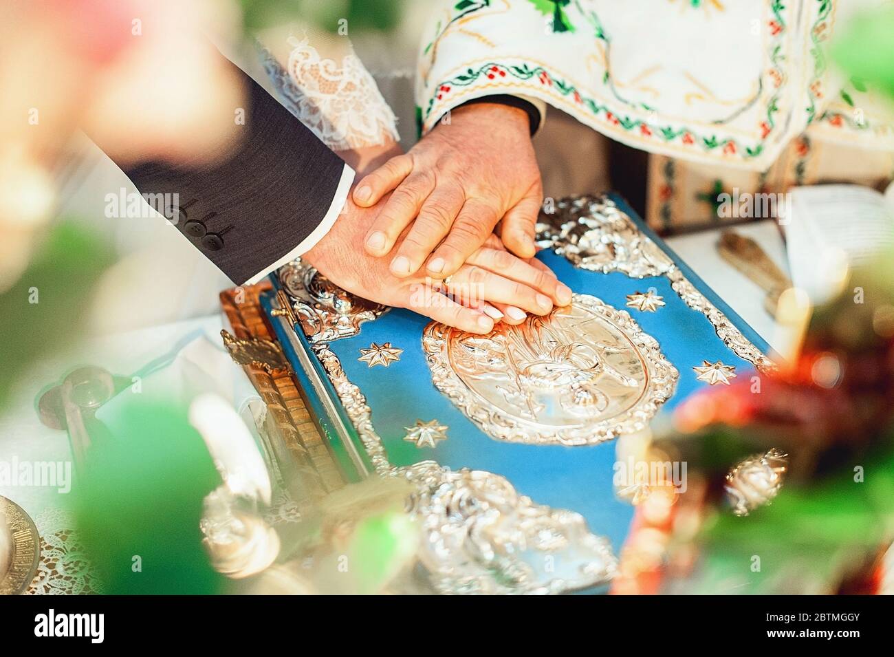 Bride and groom putting their hands on an old golden bible give a vow ...