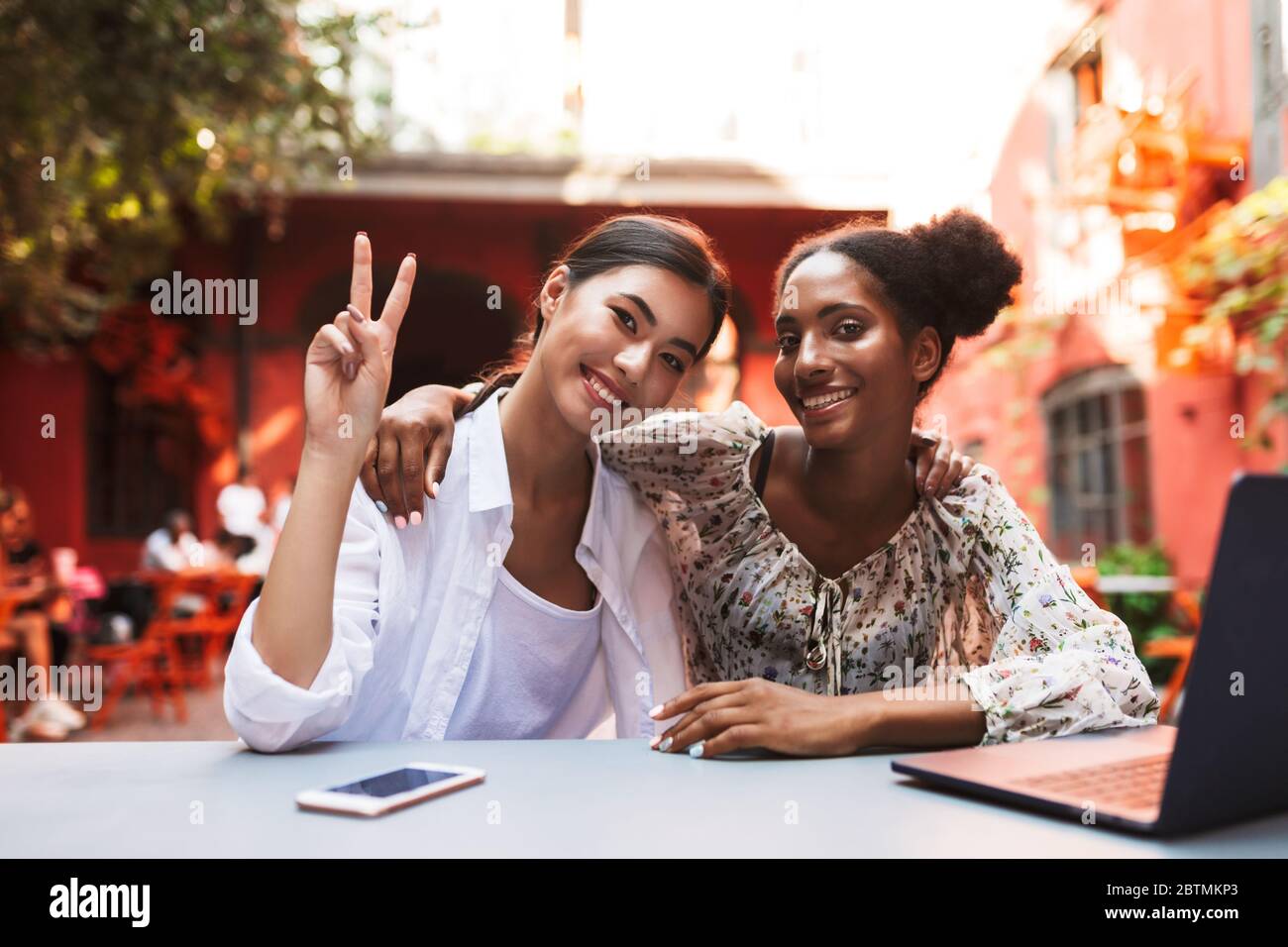 Pretty smiling girls friendly hugging each other while happily showing ...