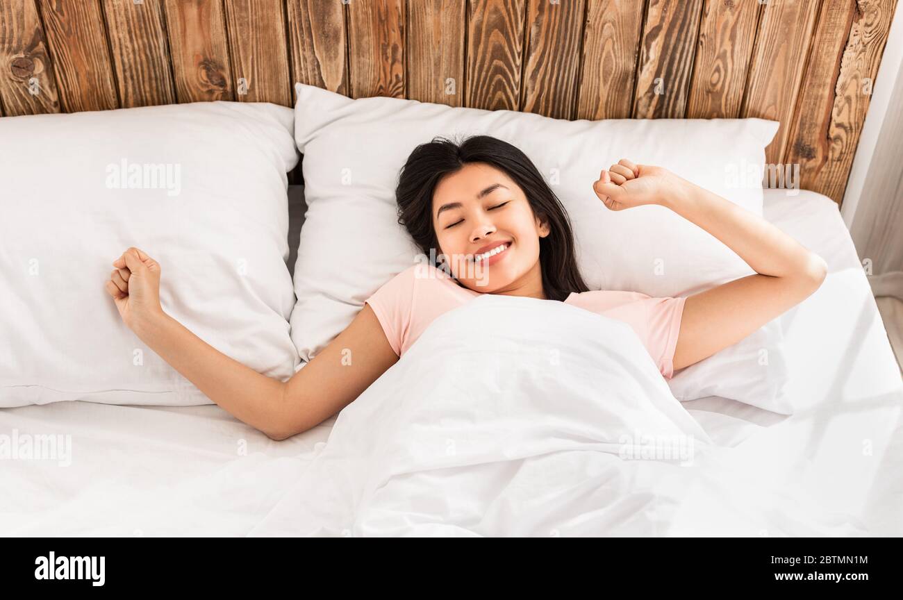 Korean Girl Waking Up Lying In Bed Stretching Hands, Above-View Stock ...