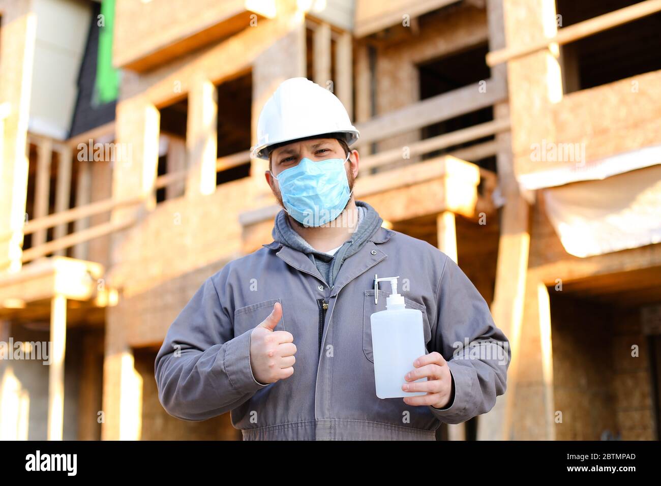 Engineer wearing mask and hardhat showing thumbs up and disinfectant ...