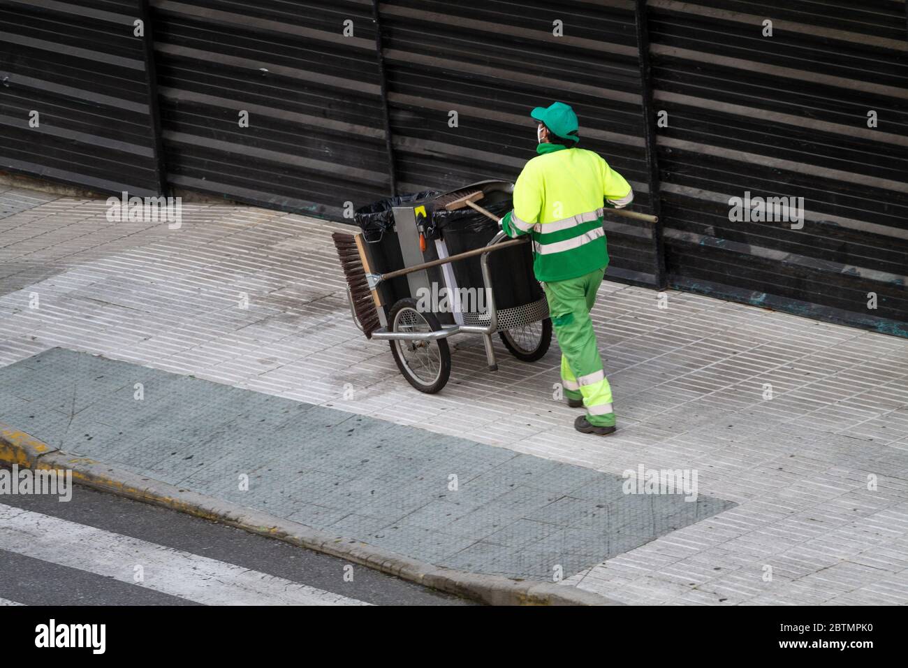 Street sweeper pushing a cart on sidewalk. Urban cleaning concept Stock ...
