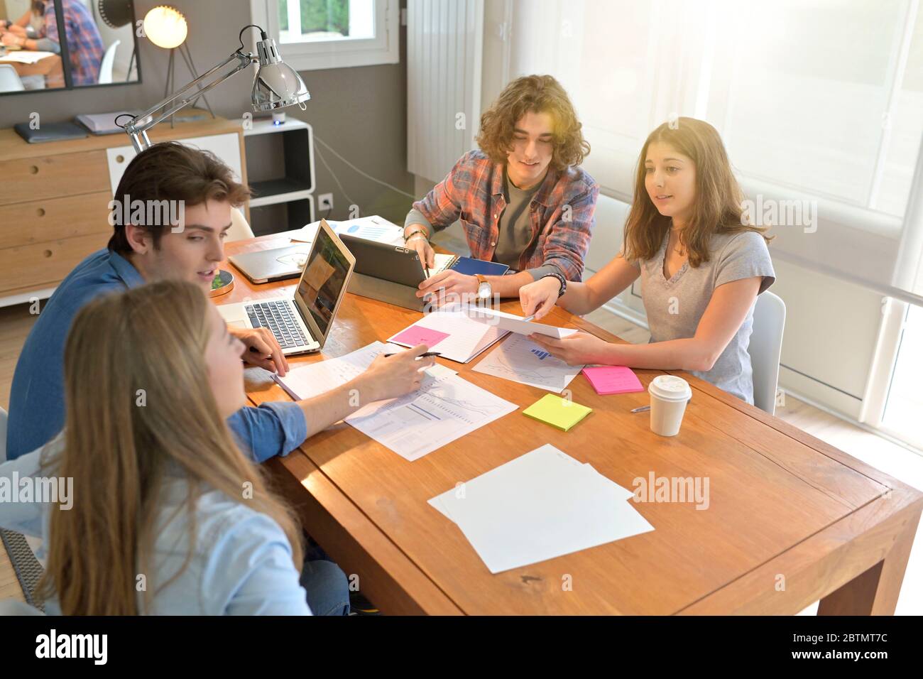 Young students meeting aroud table to work on project Stock Photo - Alamy