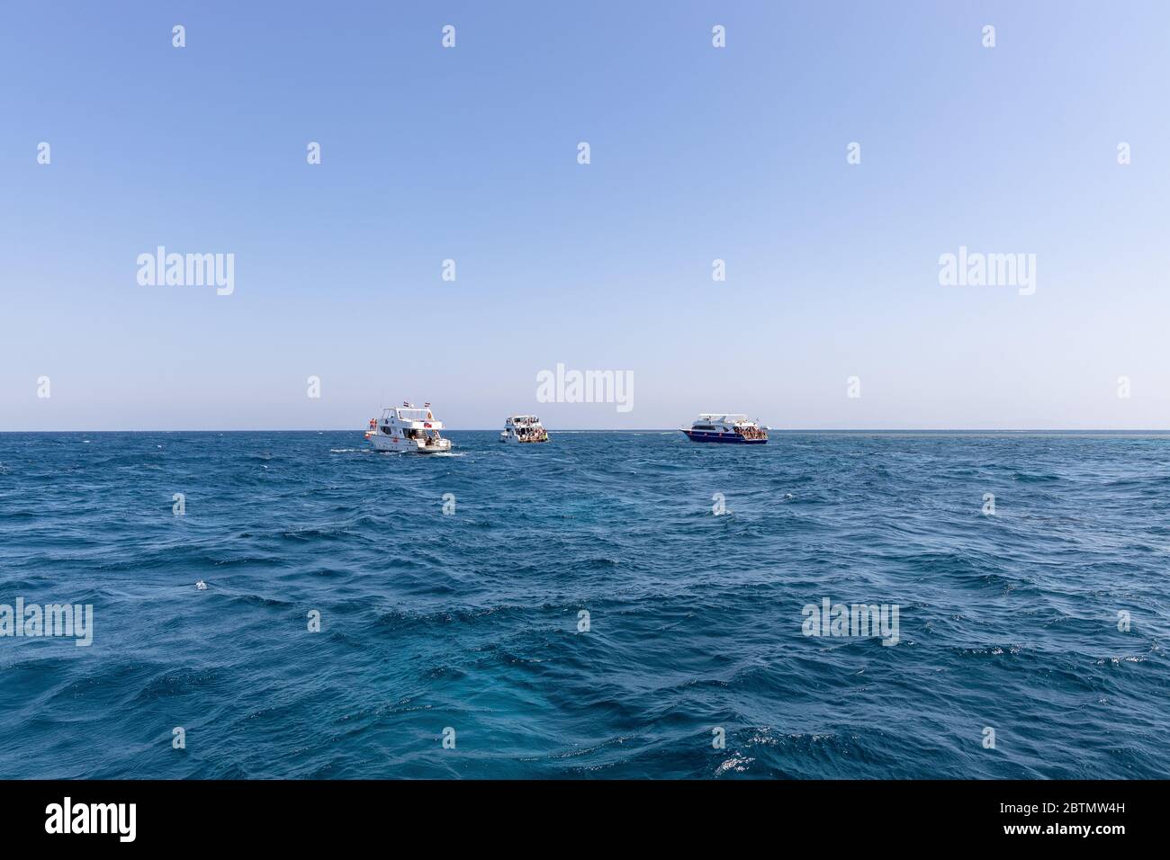 tourists boat near multicolored corrals. Corral reefs over water in Jaz ...