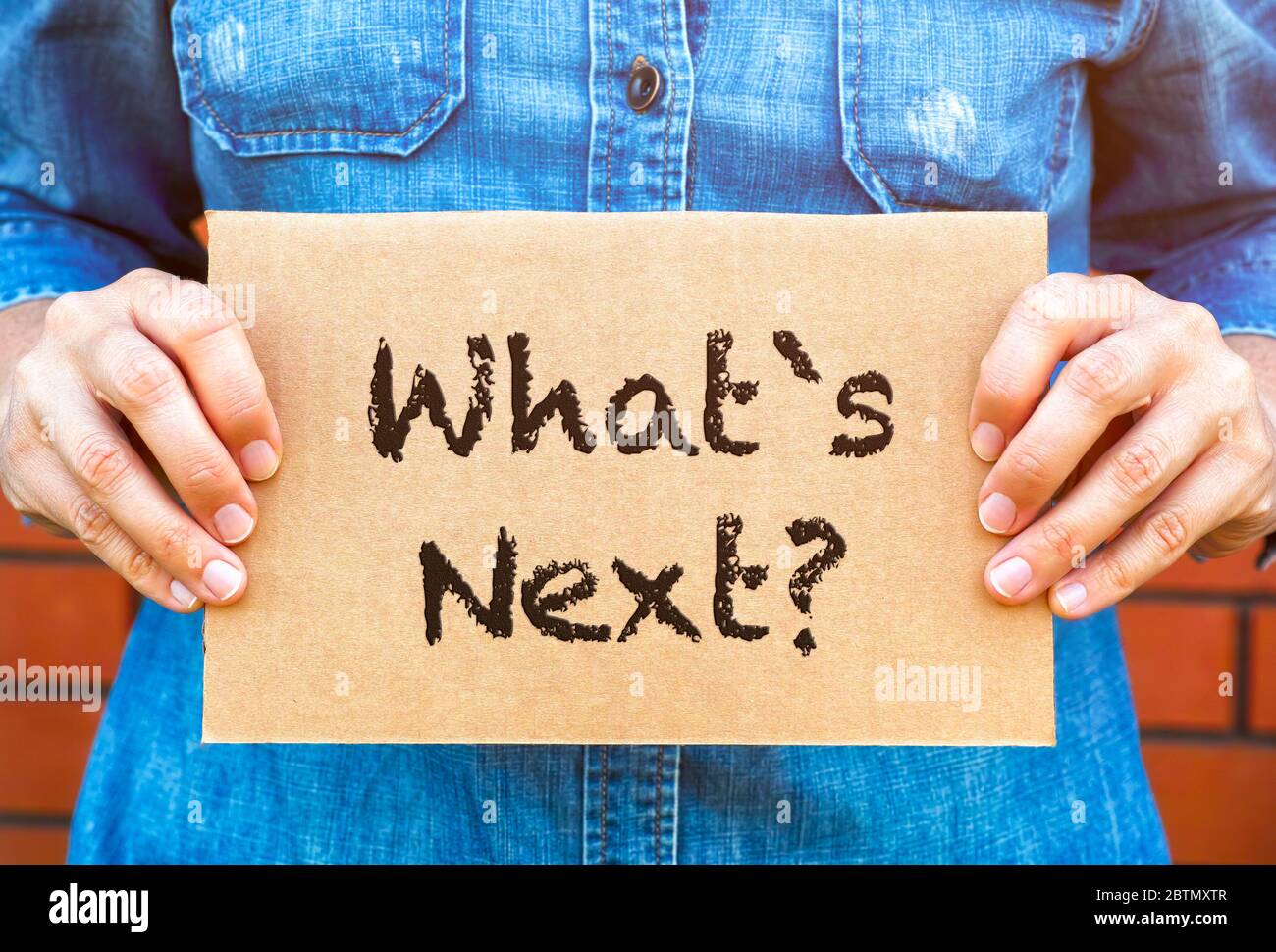 Woman hands holding piece of cardboard with words What`s Next against ...
