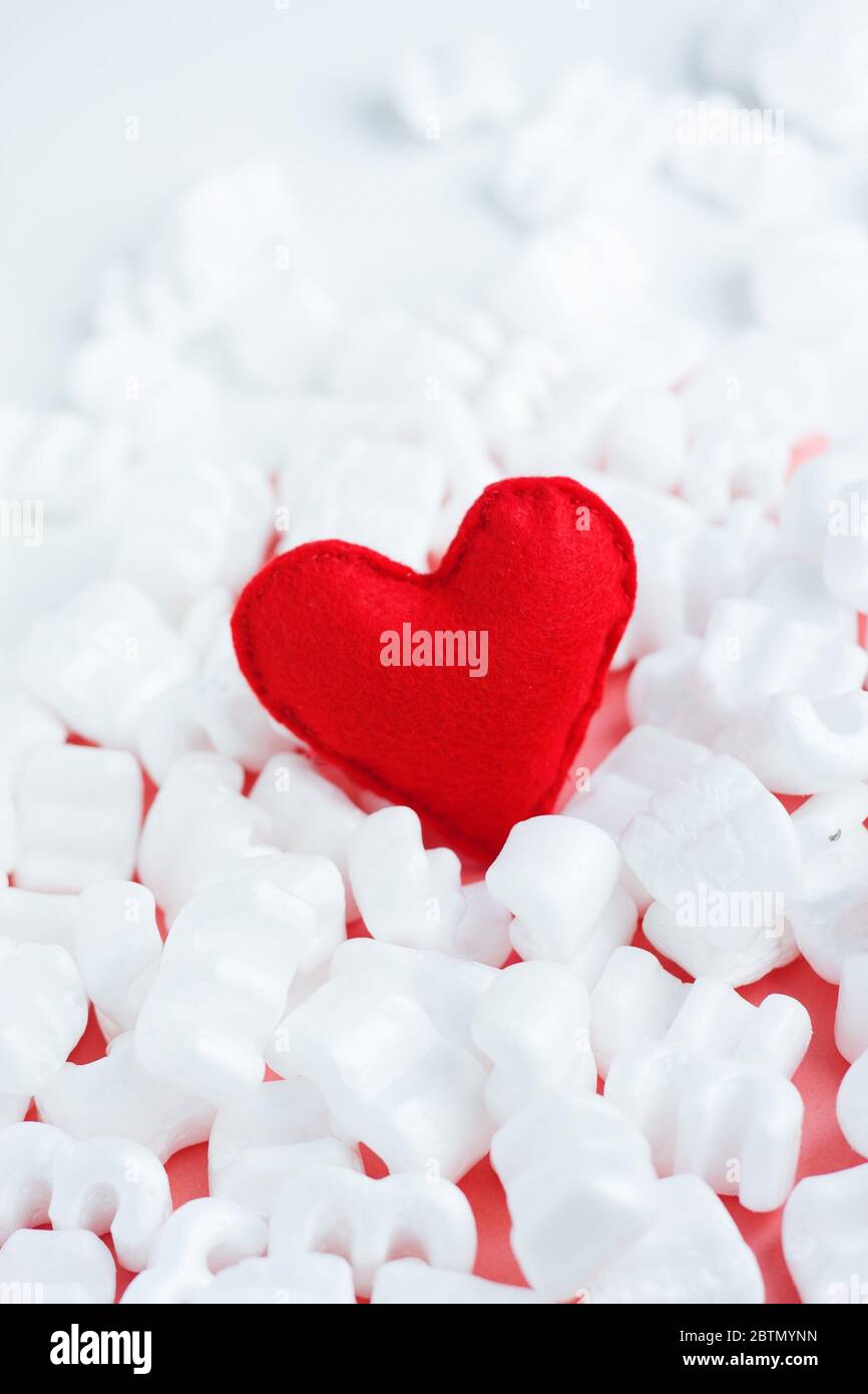 Red felt heart on white styrofoam pellets. Careful delivery with love ...