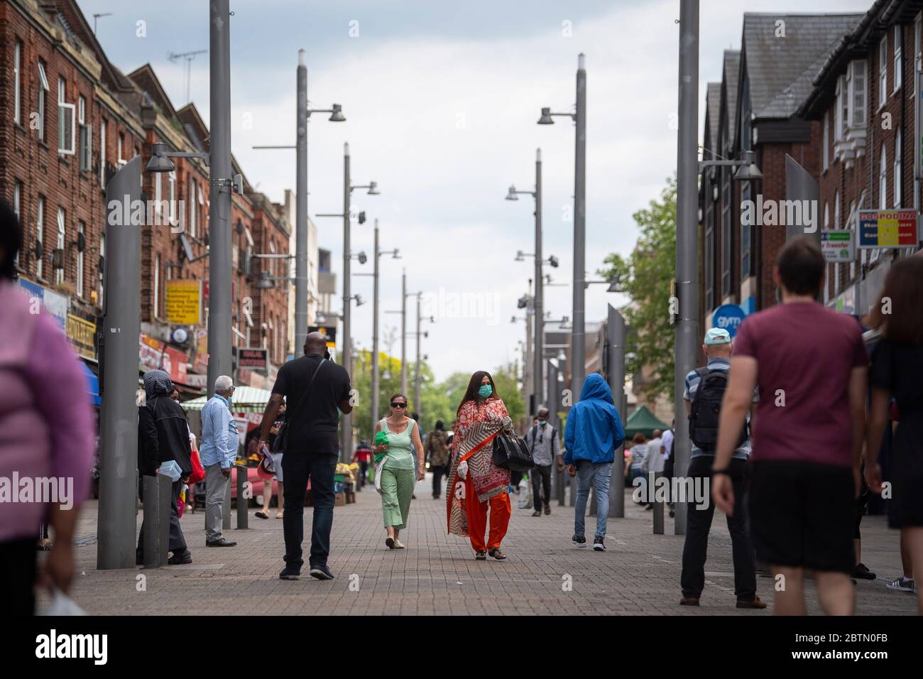 A woman wearing a face mask walks along a high street in Walthamstow ...