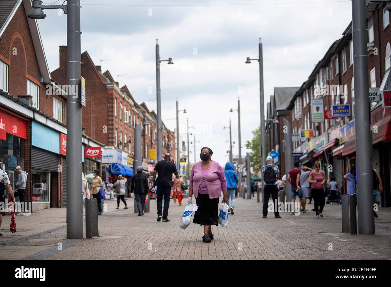 A woman wearing a face mask walks along a high street in Walthamstow ...