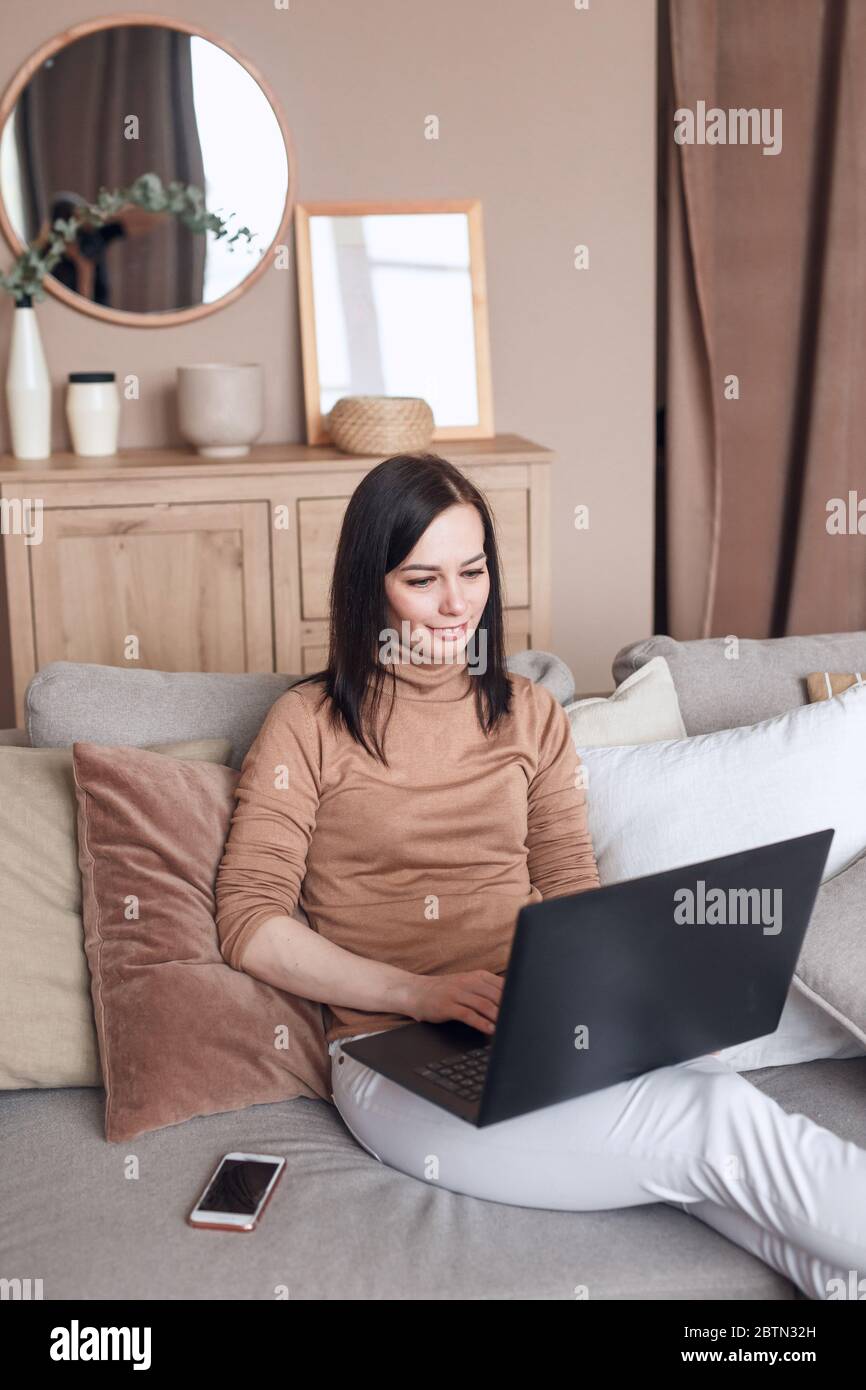 Woman work at the notebook sit down on the sofa at home Stock Photo - Alamy