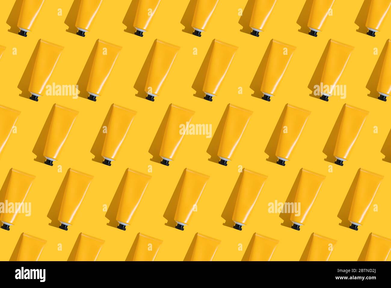 Pattern of yellow tubes of sunscreen on bright yellow background with ...