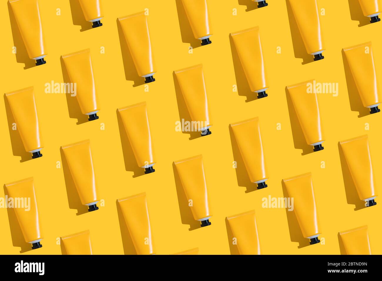Pattern of yellow tubes of sunscreen on bright yellow background with ...
