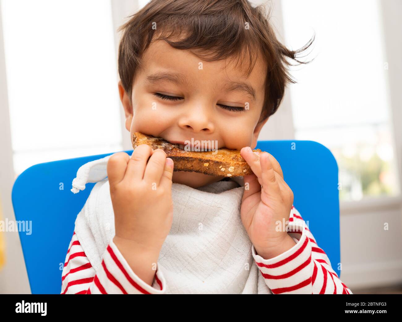 Toddler eating a toast Stock Photo - Alamy
