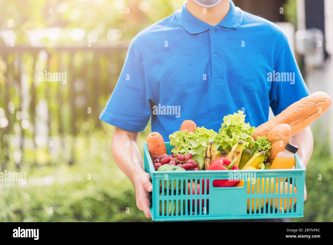 Asian grocery store delivery man wearing blue uniform and face mask ...