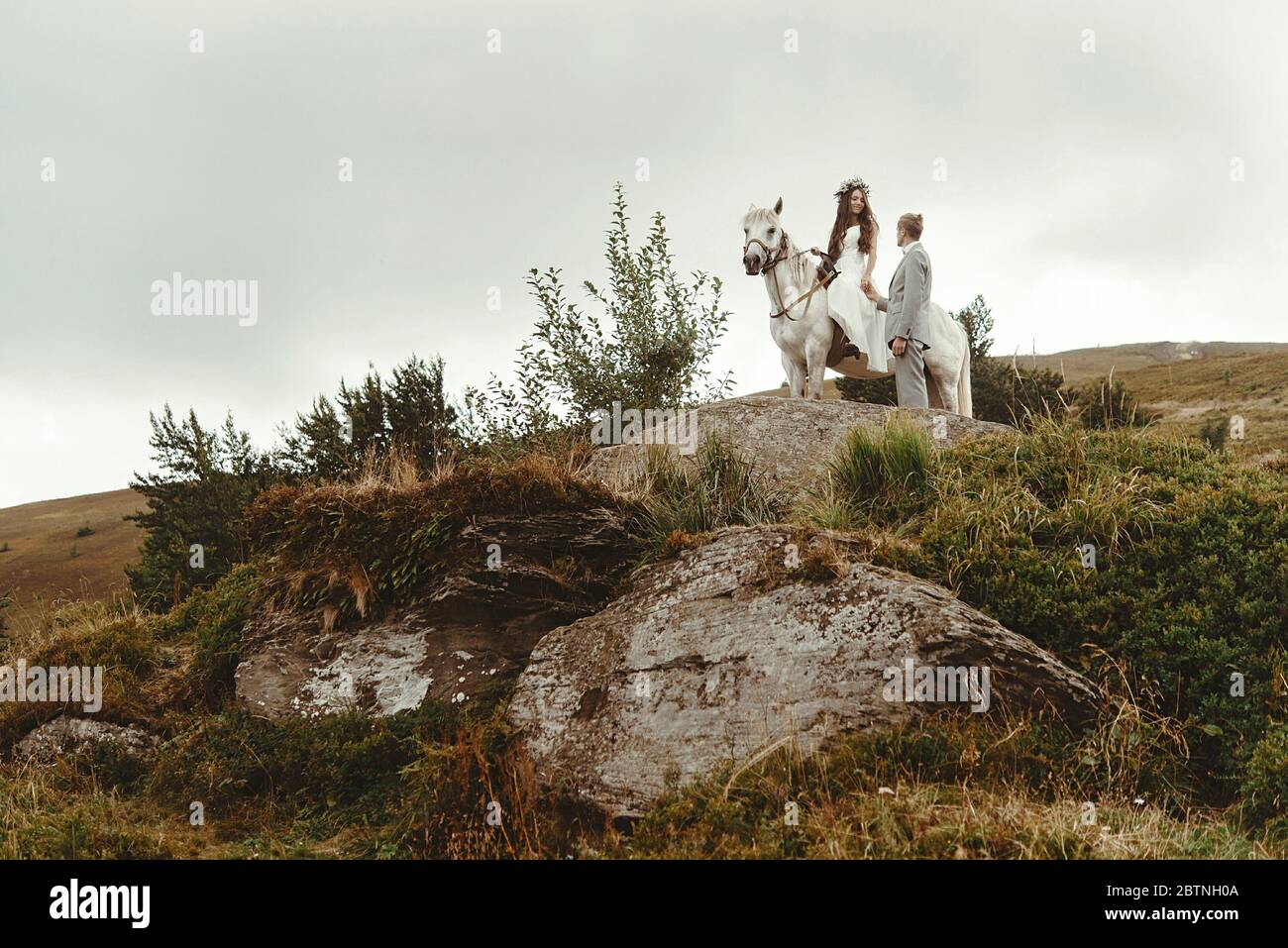 gorgeous bride riding a white horse and stylish groom, boho wedding ...