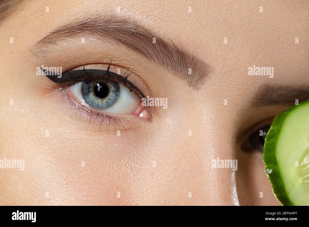 Freshness. Close up of beautiful female eyes with fresh cucumber slices ...