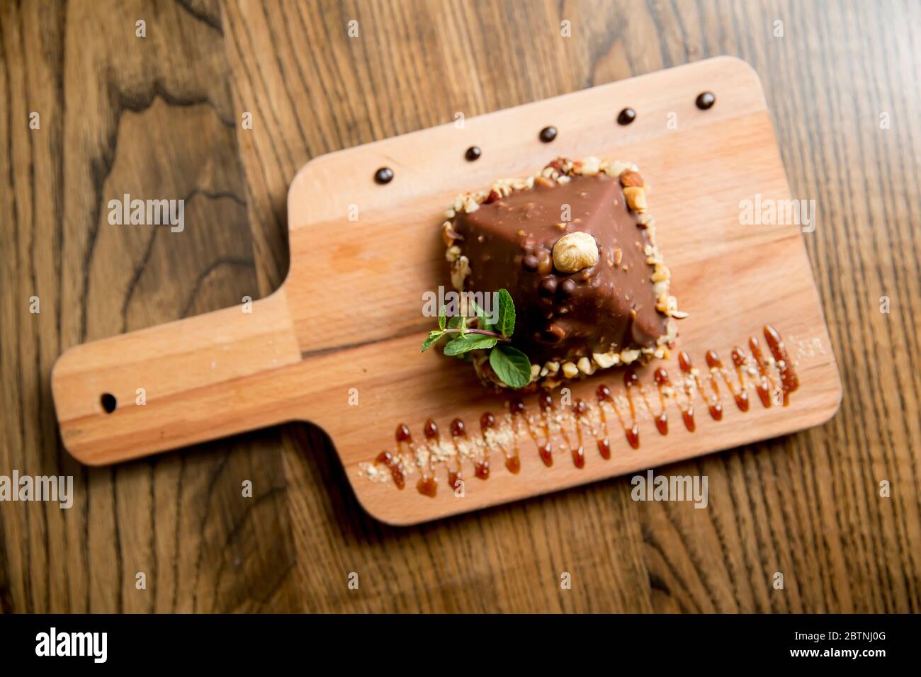 Chocolate pyramid shape cake with nuts on the wooden plate Stock Photo ...