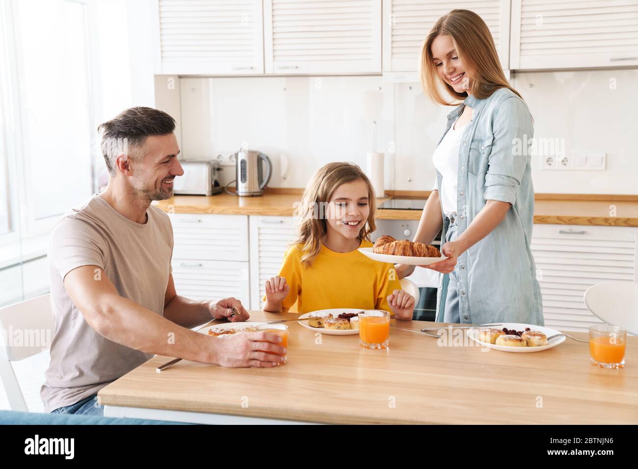 Photo of happy caucasian beautiful family smiling and eating croissants ...