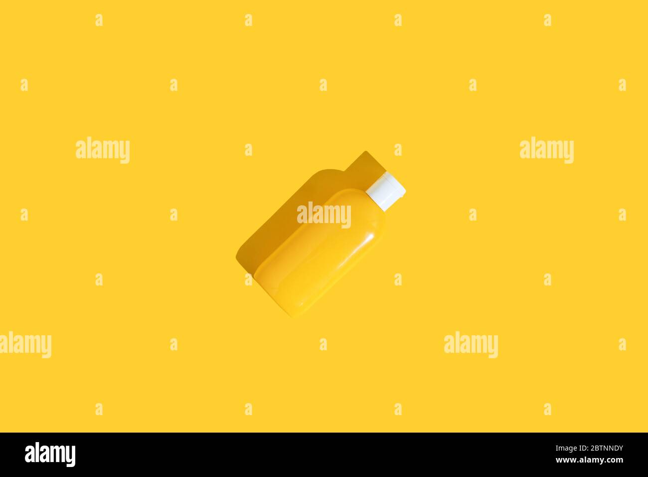 Yellow tube of sunscreen on a bright yellow background with hard shadow ...