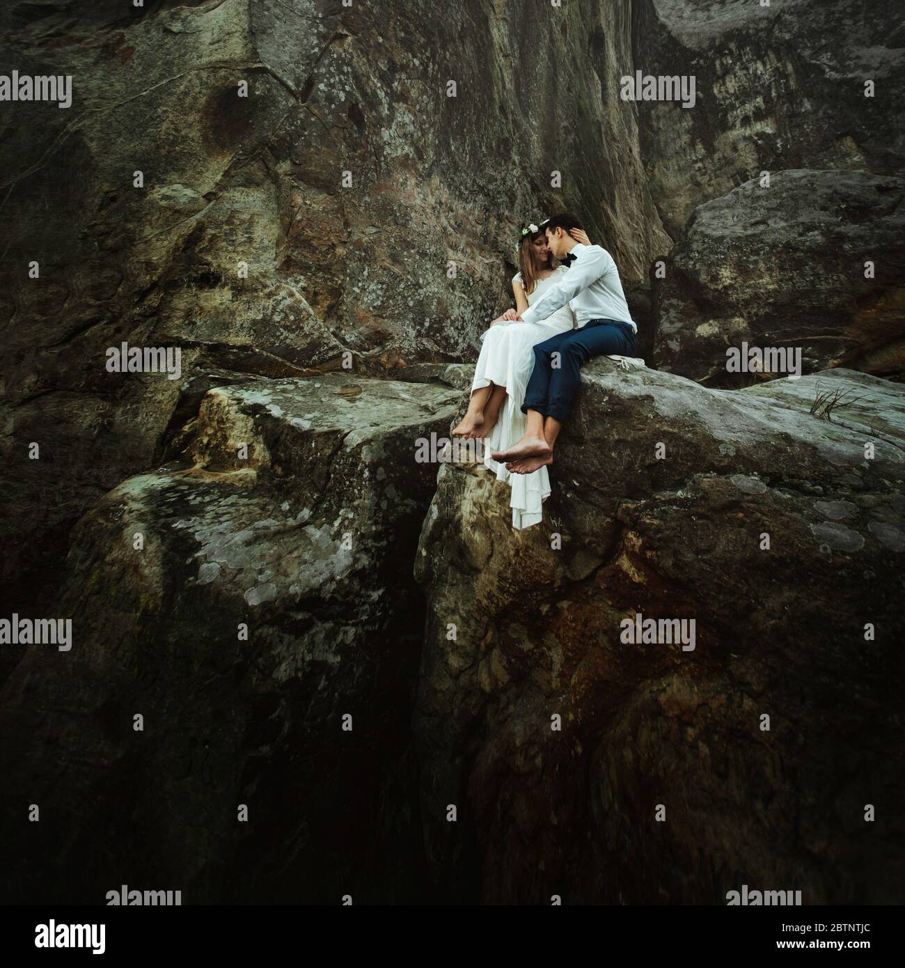 happy beautiful bride and elegant stylish groom hugging on rocks on the ...