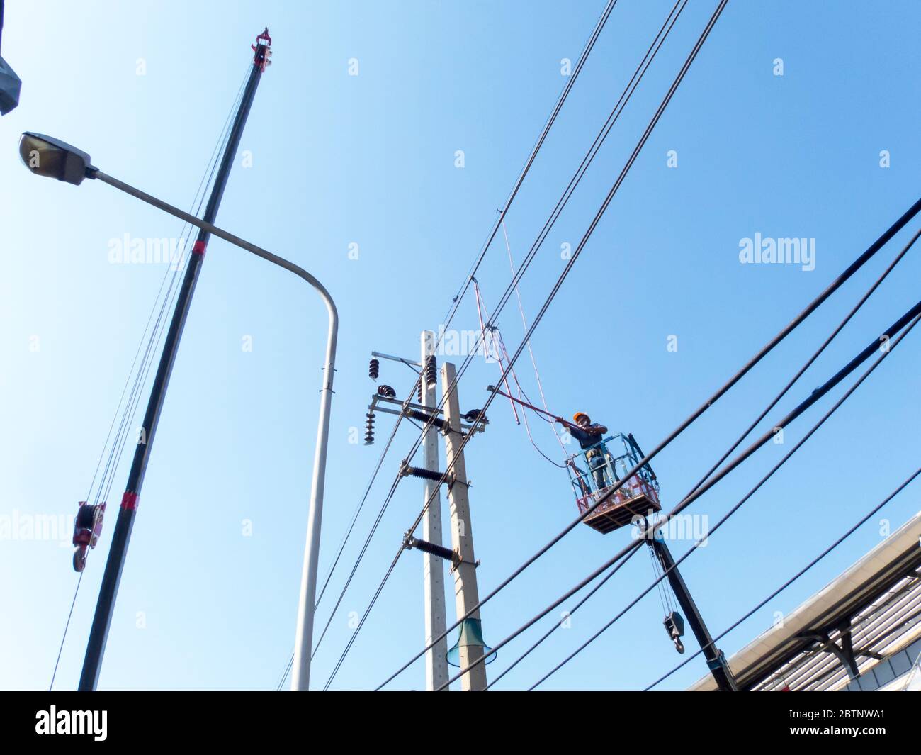 The electrician is working on the crane and the power lines on the blue ...
