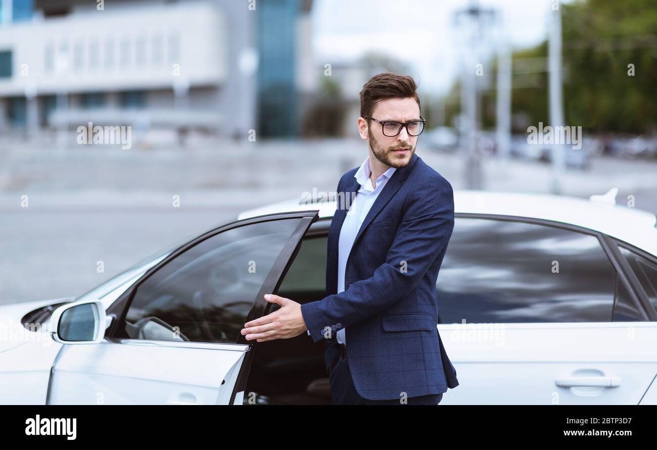 Confident businessman getting out of his car in urban city Stock Photo ...