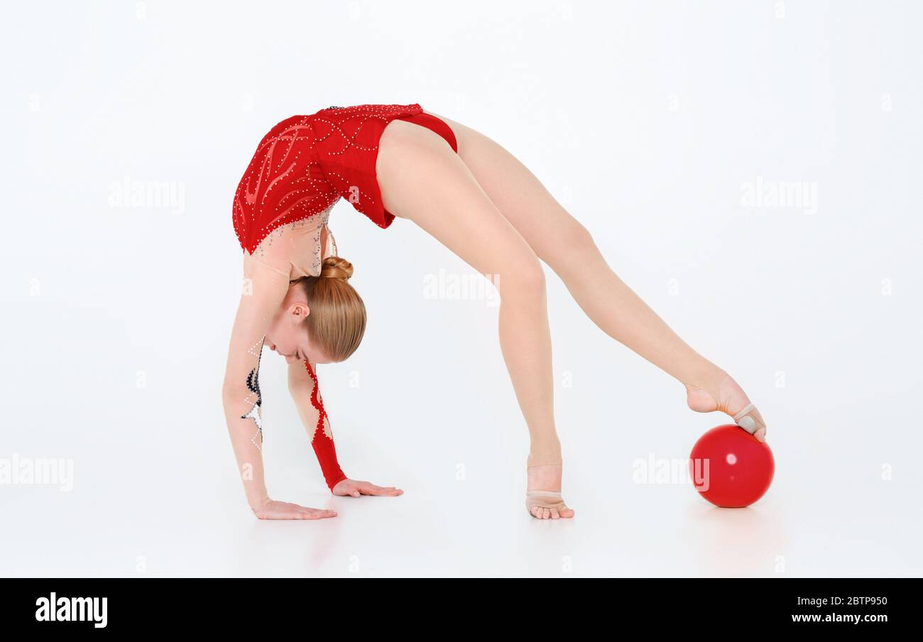 Flexible rhythmic gymnast with ball doing backbend on white background ...