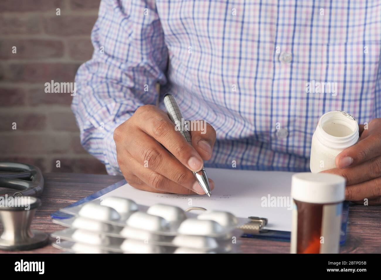 young doctor writing documents at desk in clinics office with copy ...