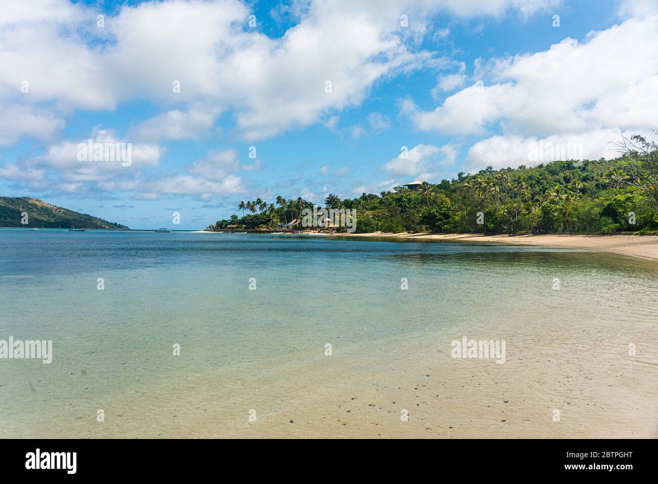 Wide angle view of the flat water bay of a tropical island. Palm trees ...