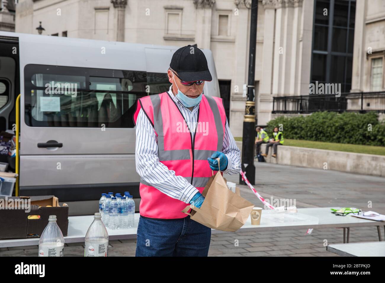 27/05/2020, Trafalgar Square, London UK. Volunteer waits to hand over ...