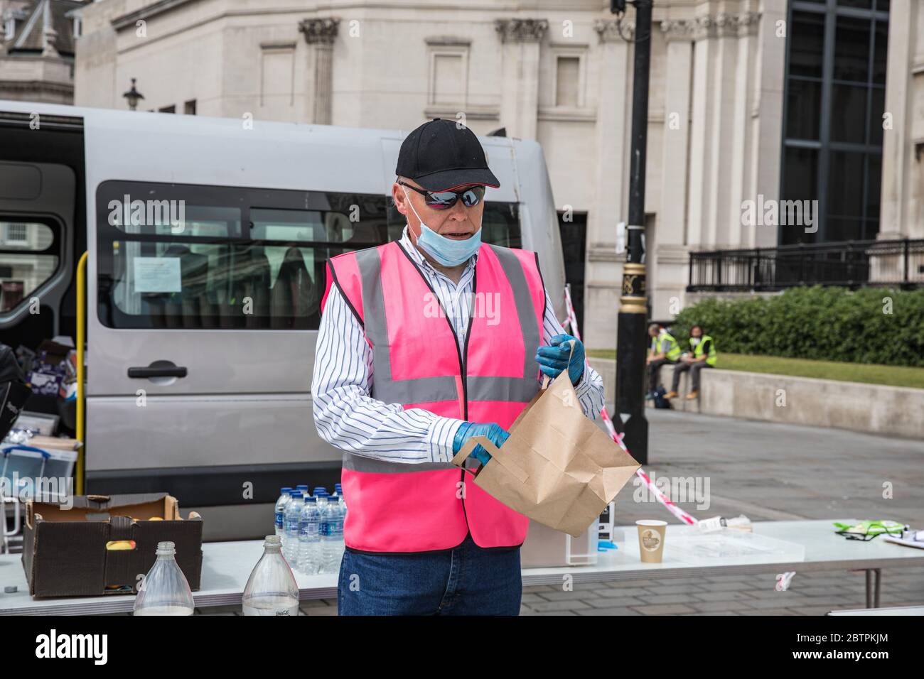 27/05/2020, Trafalgar Square, London UK. Volunteer waits to hand over ...