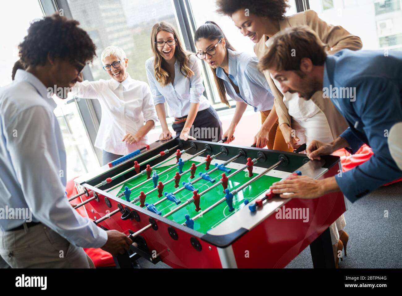 Employees playing table soccer indoor game in the office during break ...
