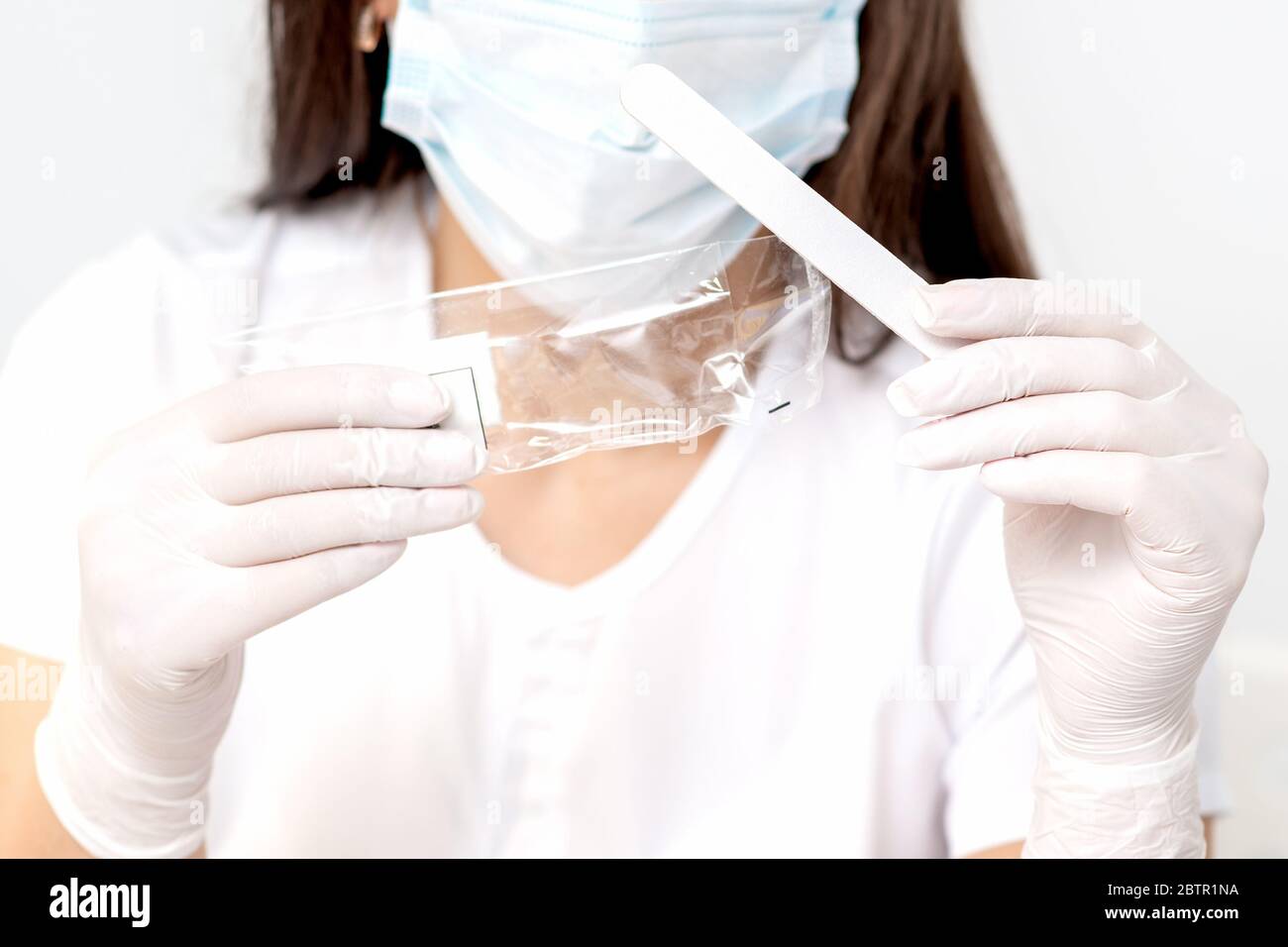 Portrait of a manicure master in a white coat and white mask on her ...