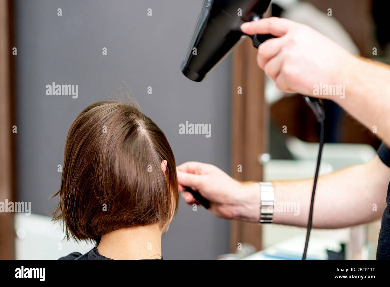 Hairdresser's hands drying short brown hair with blow dryer in hair ...