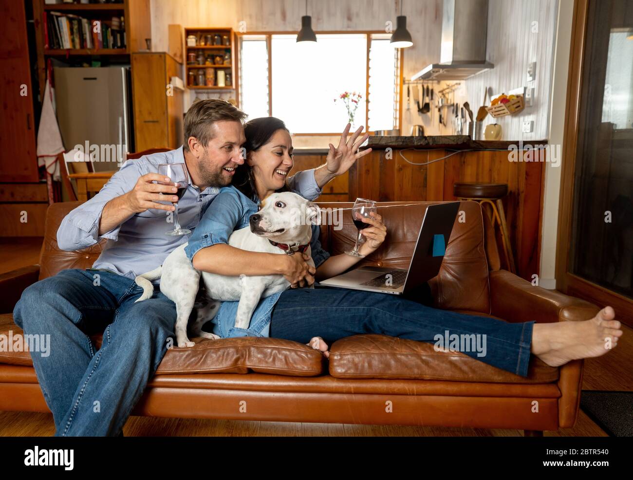 Happy couple and pet dog video calling friends using laptop. Man and ...