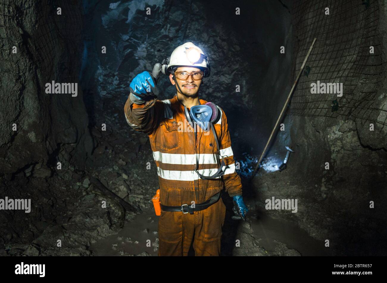Miner in the mine. Well-uniformed miner inside mine raising thumb ...
