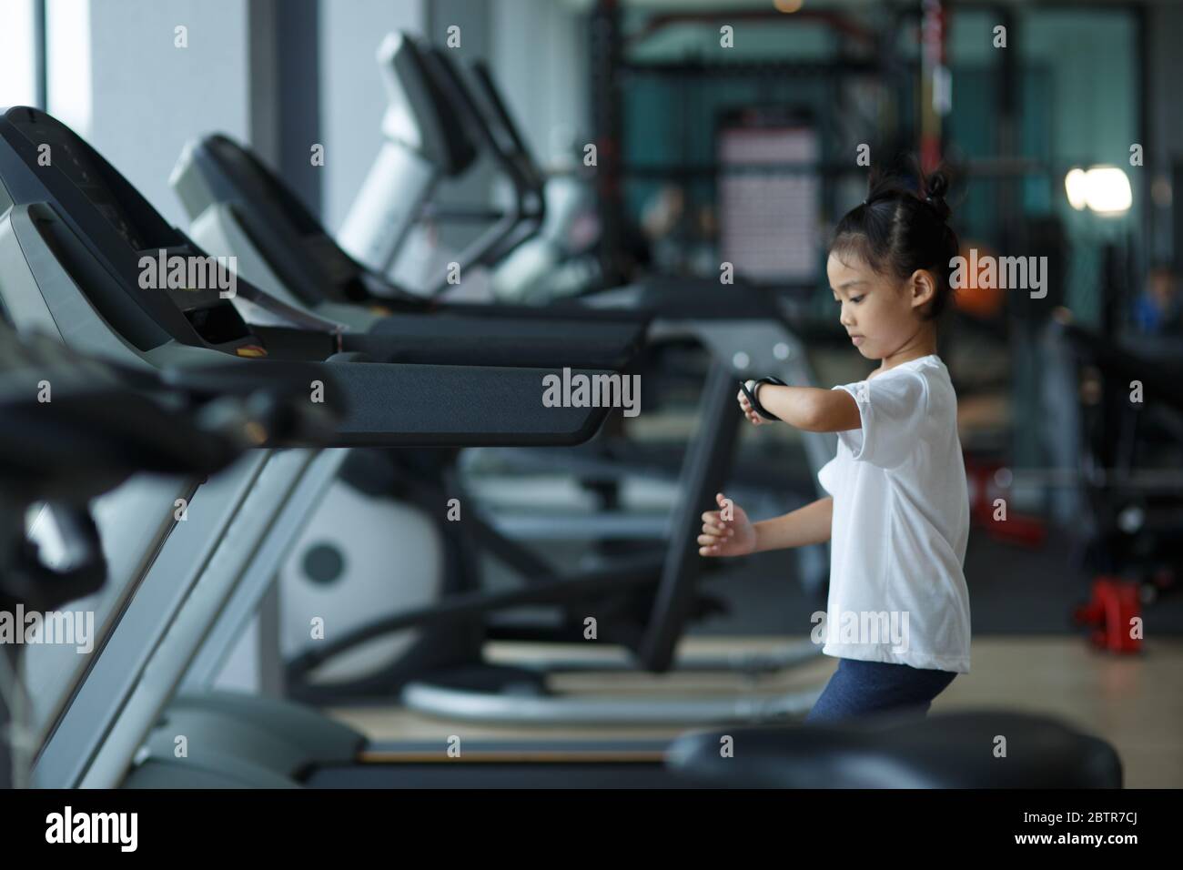 A little girl is running on the treadmill. Children's sport concept ...