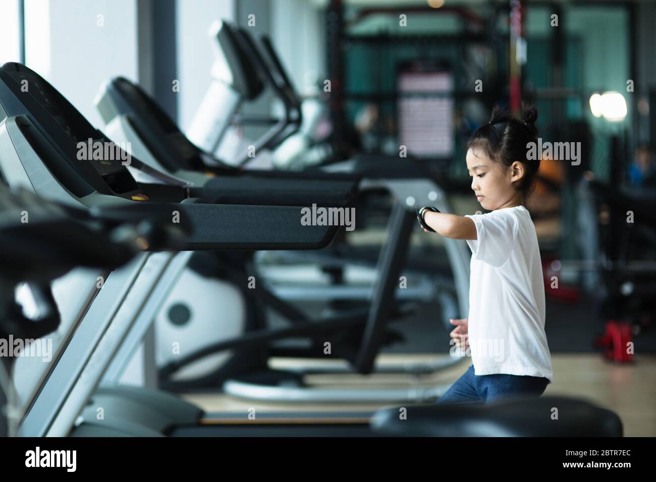 A little girl is running on the treadmill. Children's sport concept ...