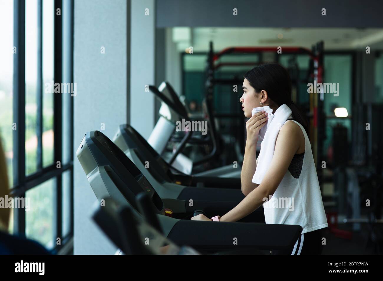 Side view of beautiful girl running on treadmill at gym Stock Photo - Alamy
