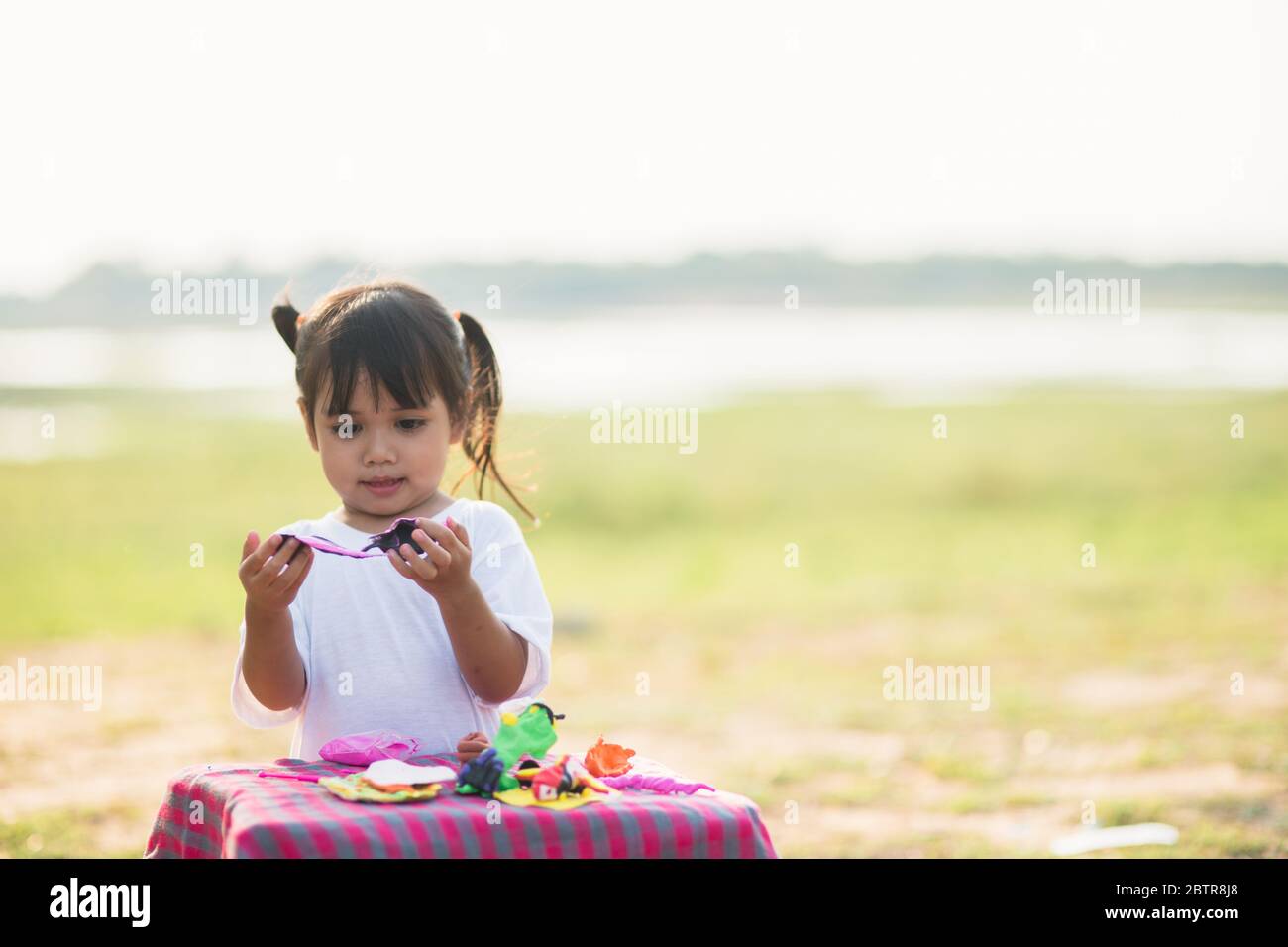 Cute Little girl enjoy playing play doh at park Stock Photo - Alamy