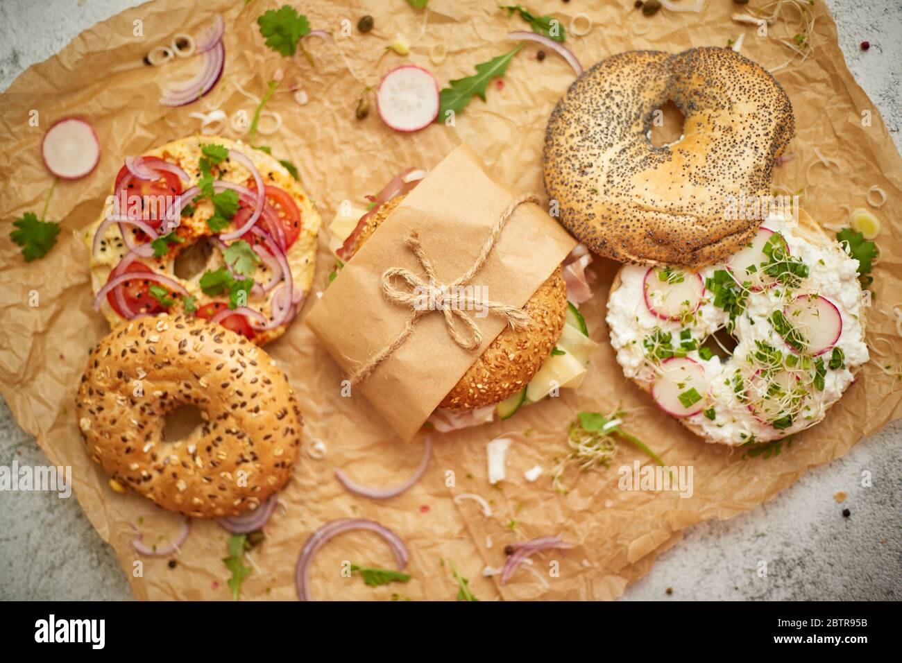 Bagels with ham, cream cheese, hummus, radish wrapped in brown baking ...