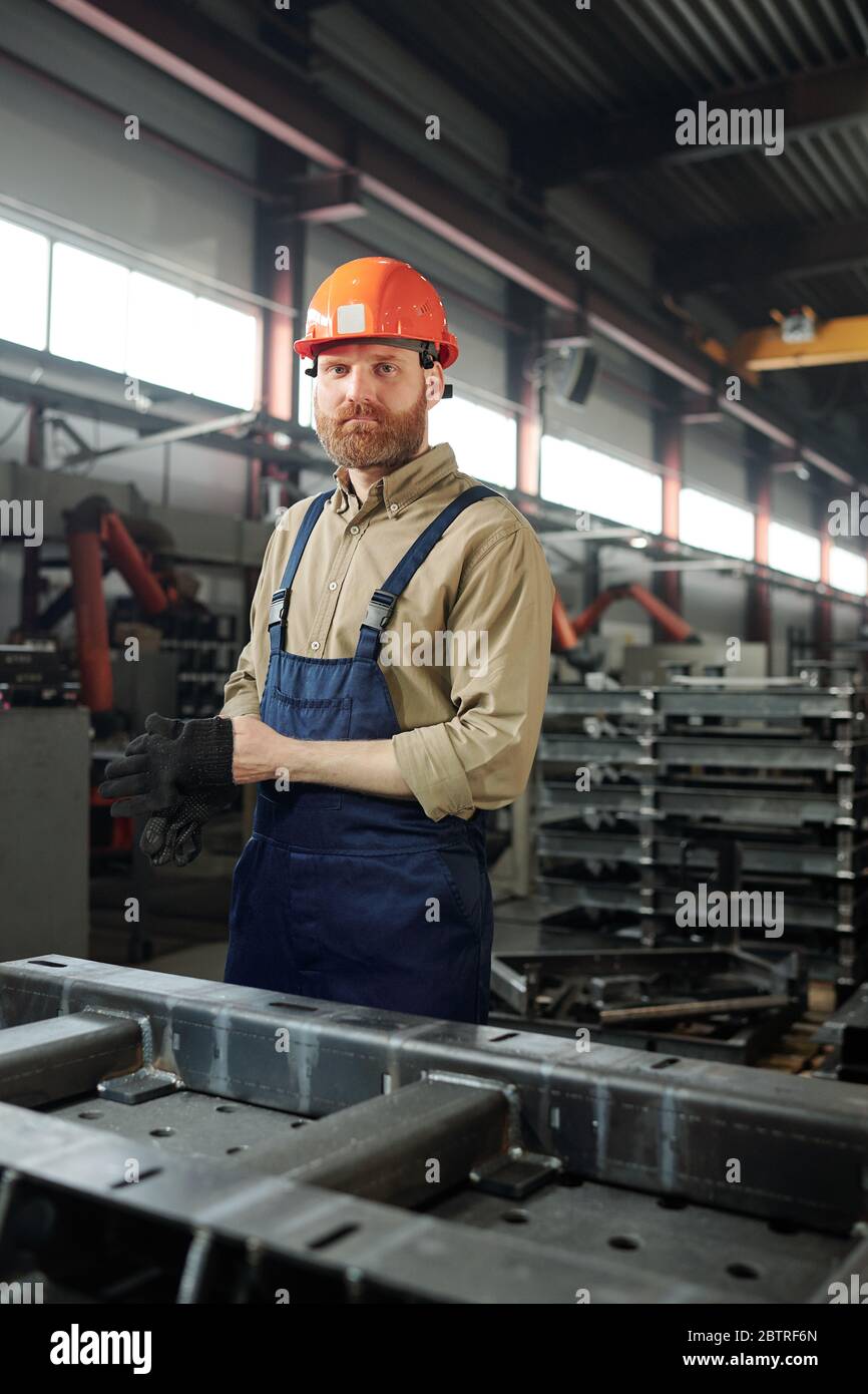Portrait of serious bearded manufacturing worker in hardhat and ...