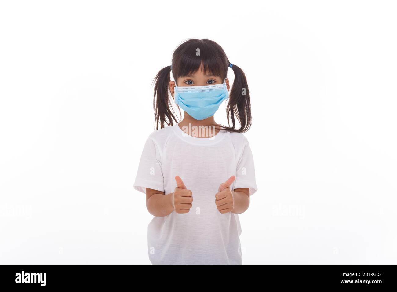 Little asian girl wearing mask for protect pm2.5 and show thumbs up gesture for good air outdoor ...