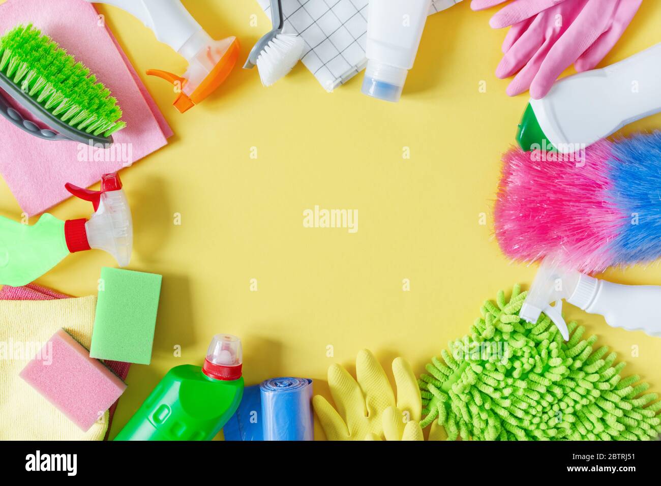 Bottles of detergent and cleaning tools on yellow background top view ...