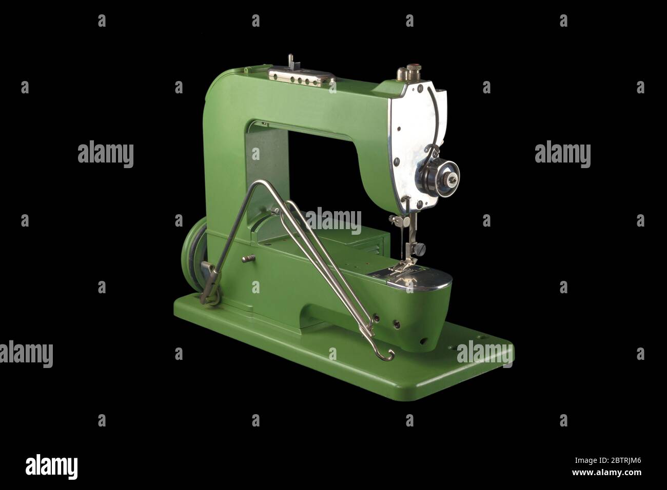 side view of an old vintage green sewing machine on black background ...