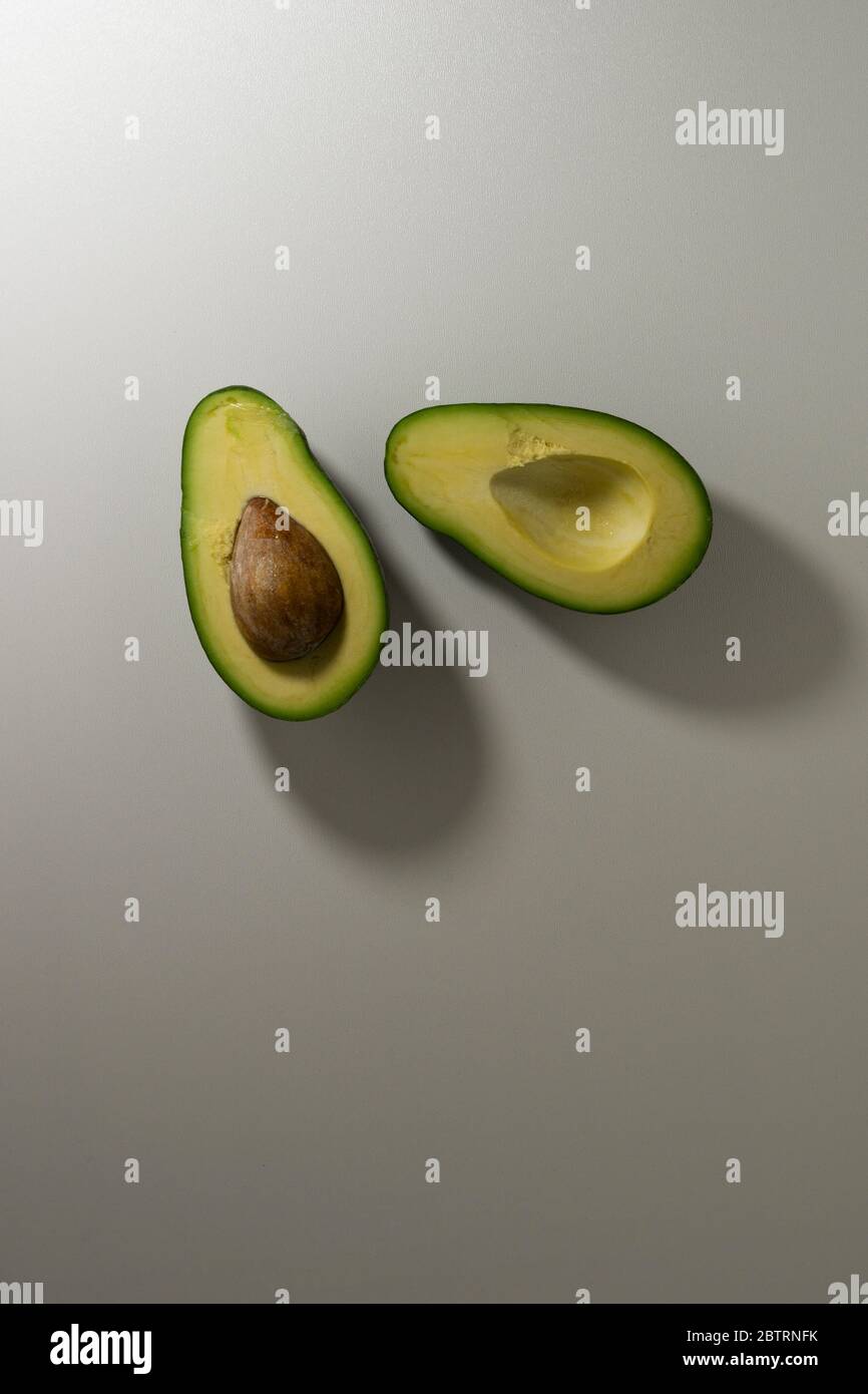 Two halves of avocado fruit with kernel on a light background. top view ...