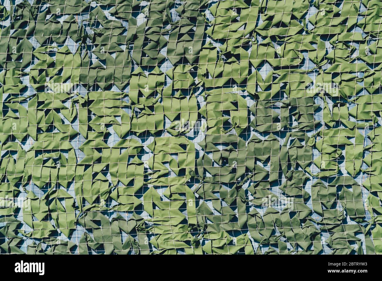 The texture of a camouflage mesh in shades of green with thin squares ...
