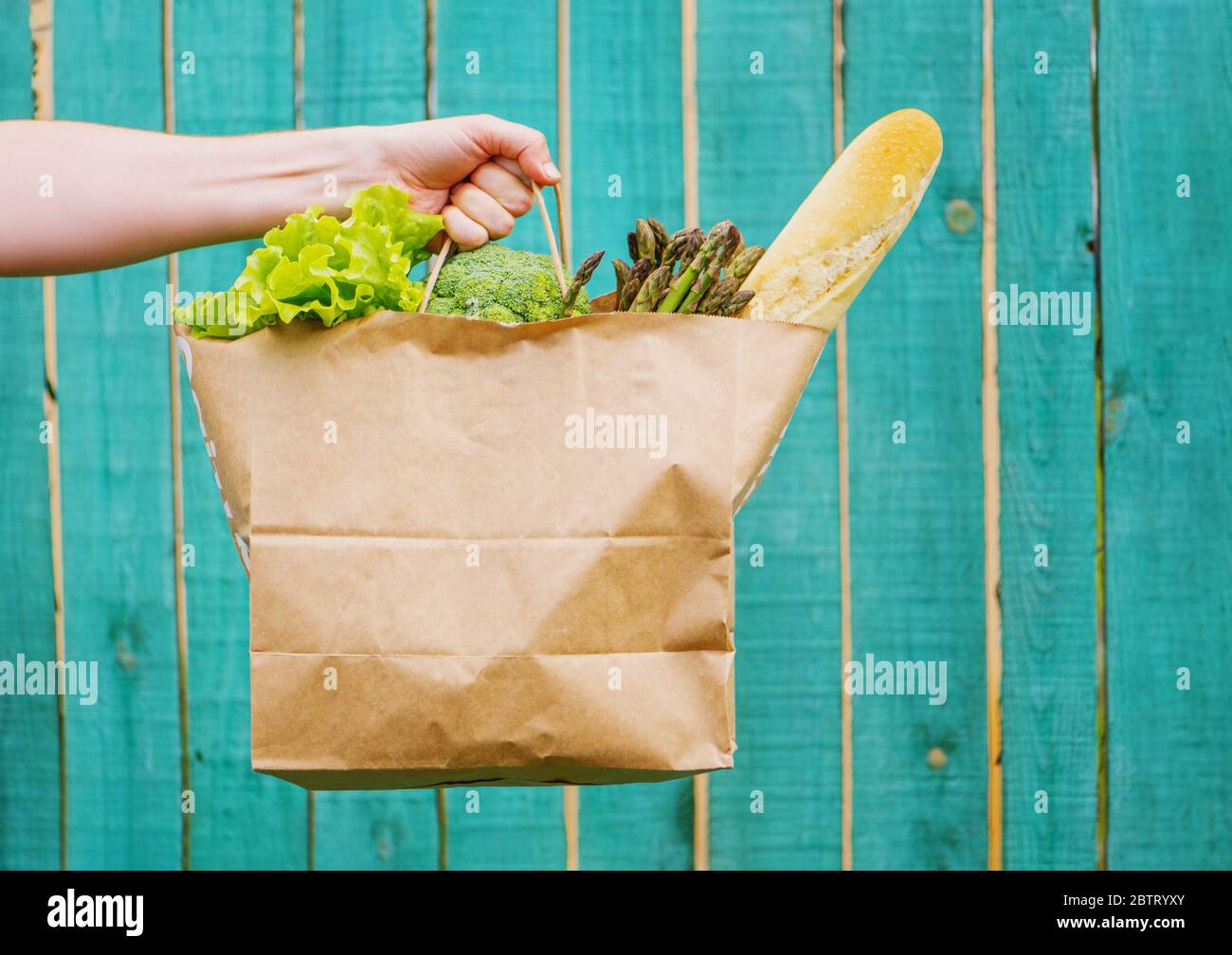 Hand holding paper bag with vegetables and baguette Stock Photo - Alamy