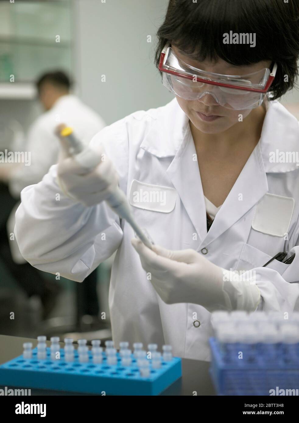 Syringe in the gloved hand of a lab technician precisly measuring a ...