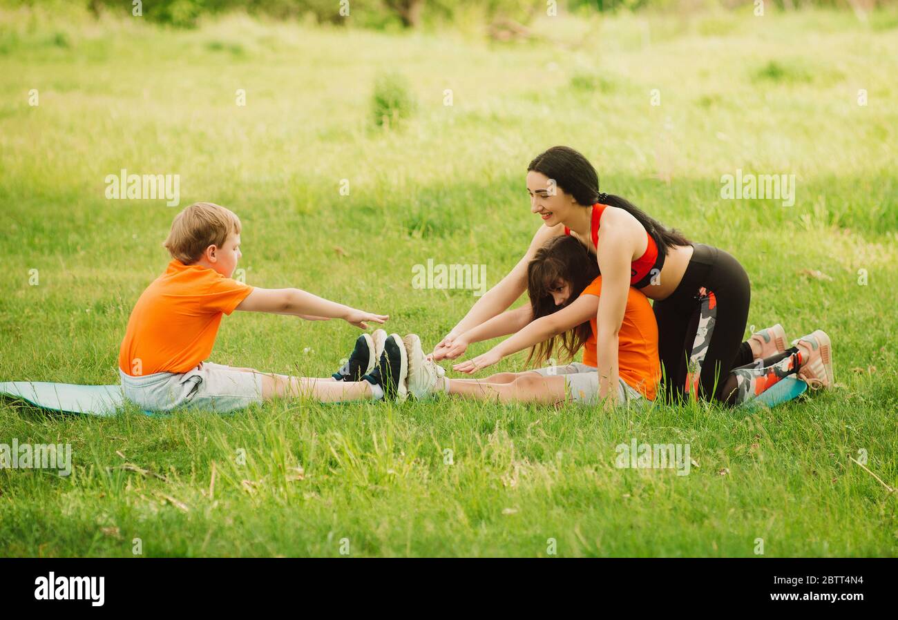 The mother helps children complete the exercise. Make sports open air ...