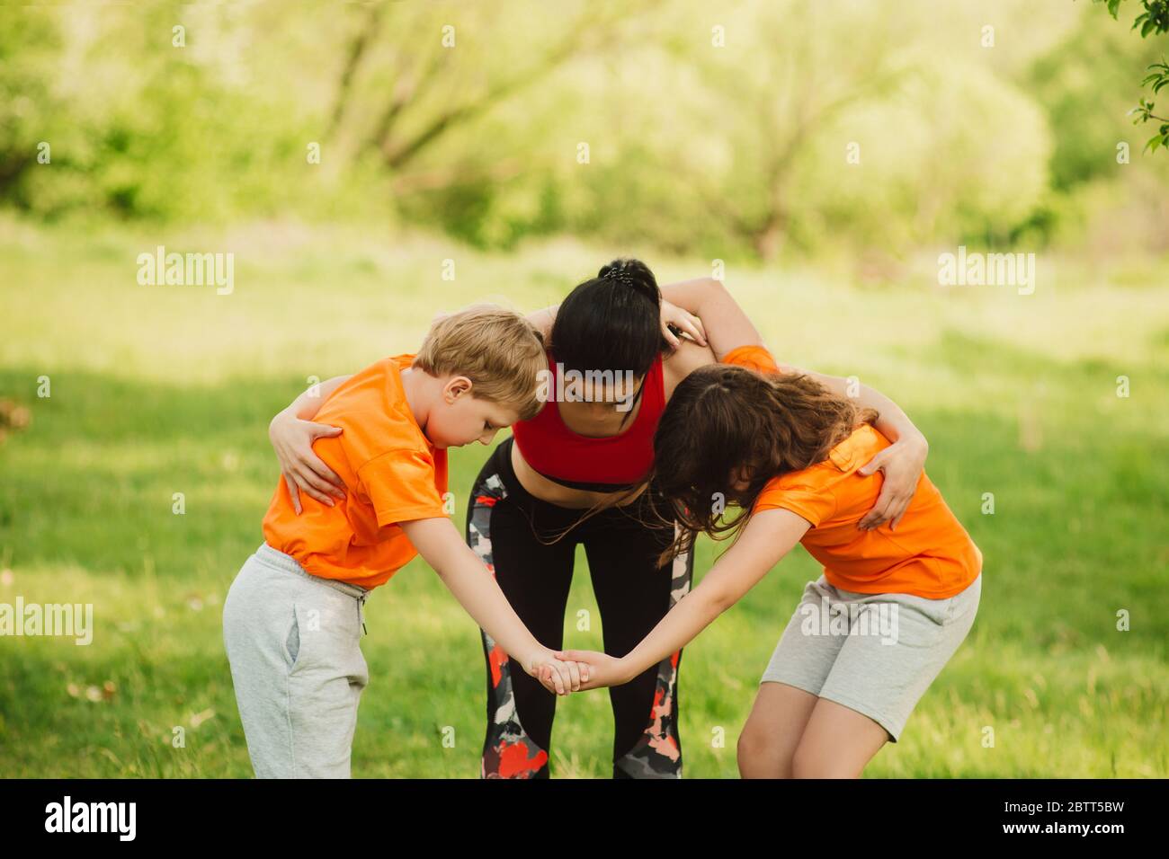 Fitness coach helps children complete the exercise. Make sports open ...