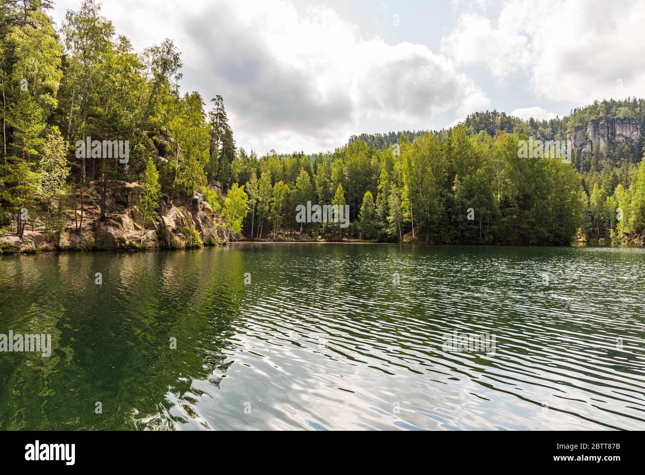 Green water of calm forest lake between small mountains covered with ...